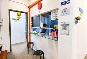 Uma área de recepção com balcão de vidro, um relógio e uma porta com uma placa.