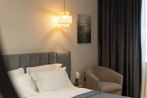 Quarto de hotel com cama, uma cadeira, luminária na parede e um quadro.