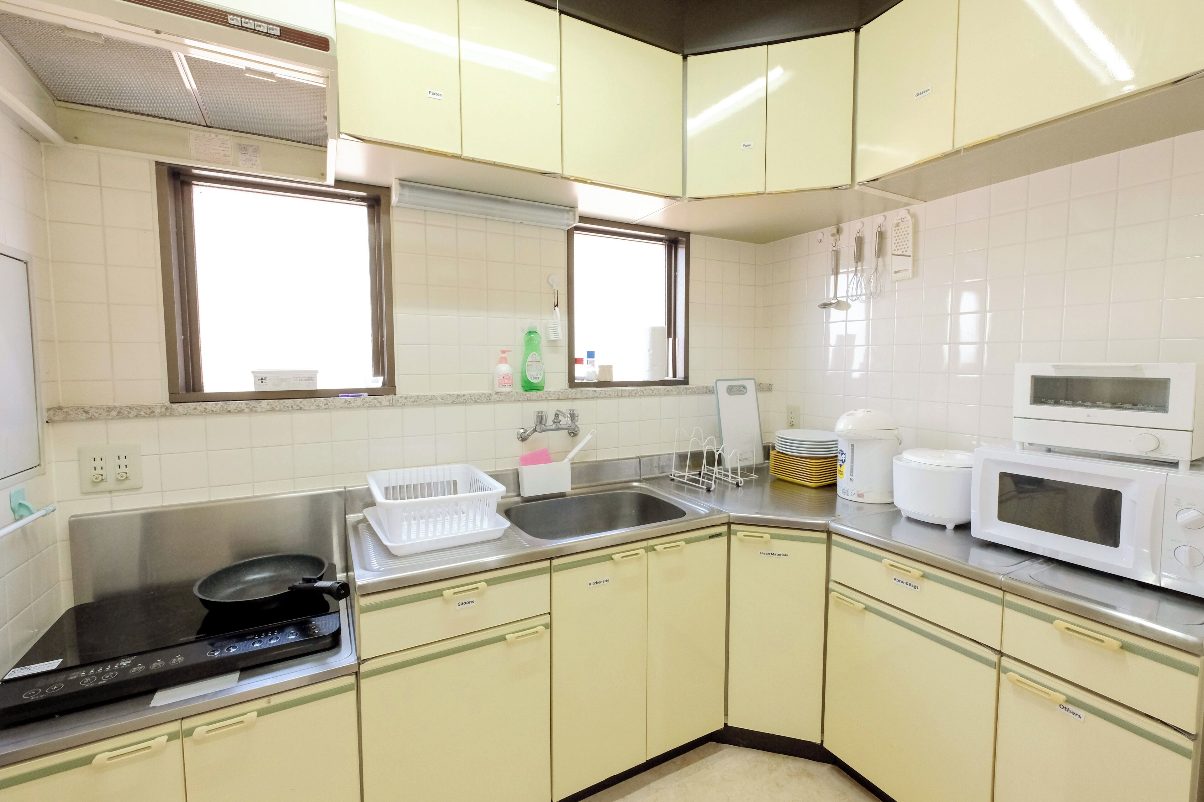 Cozinha com fogão, micro-ondas, pia e armários identificados para organização.