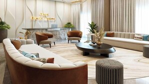 Uma área de recepção moderna com balcão, sofás, poltronas e um candelabro.