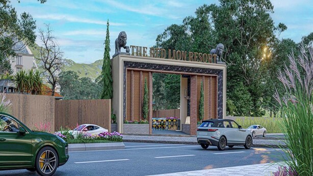 Um edifício moderno com um letreiro de entrada em destaque, uma estátua de leão e um caminho de acesso pavimentado com carros estacionados.