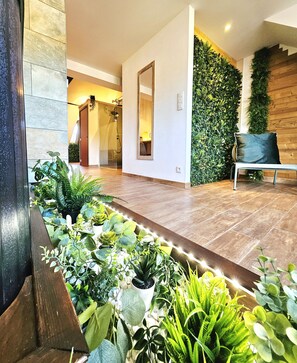 Um interior moderno com sala de estar, um banco de madeira e diversas plantas em vasos.