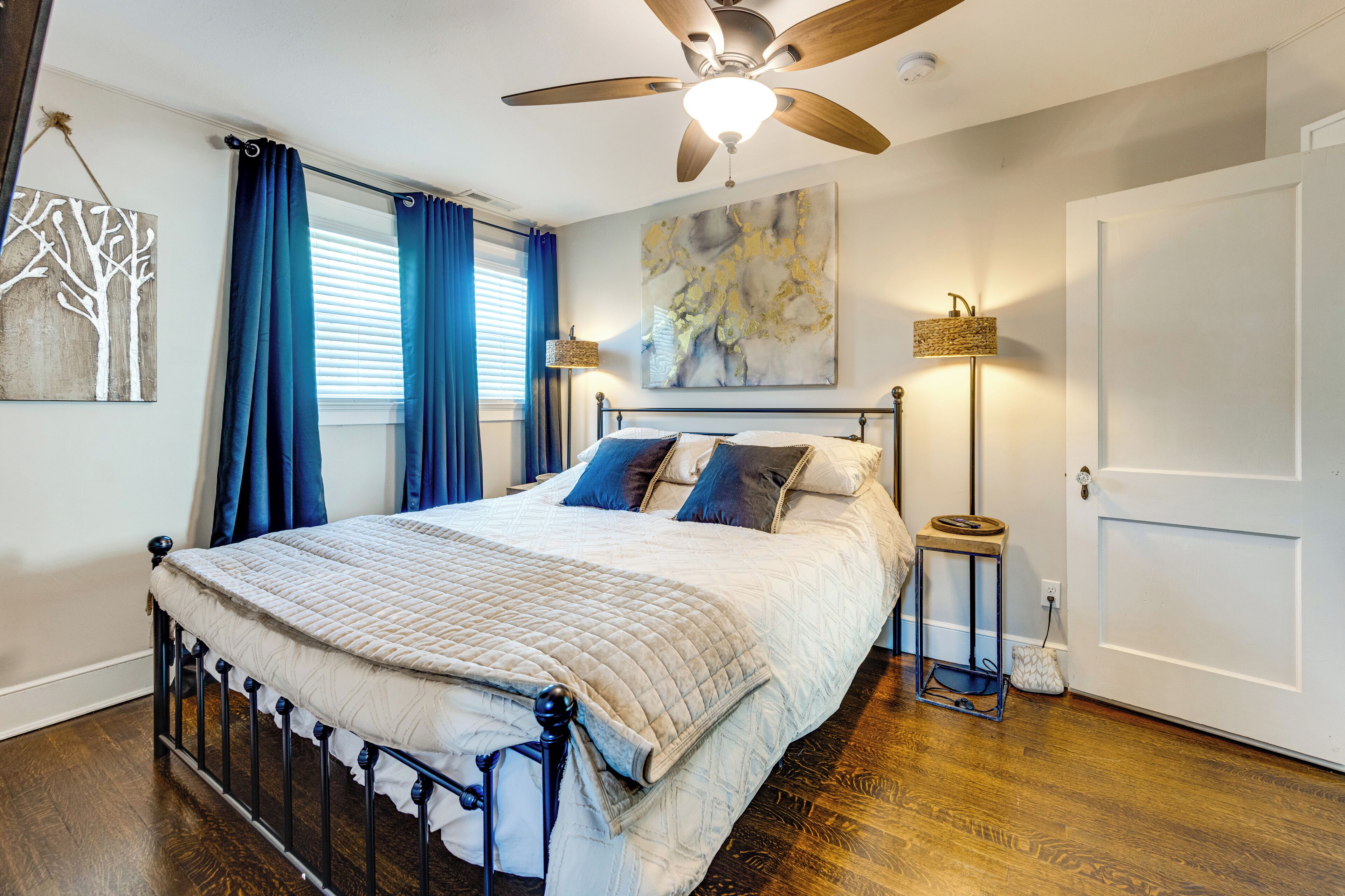Quarto com cama, ventilador de teto, luminária de chão e porta.