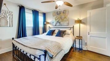Quarto com cama, ventilador de teto, luminária de chão e porta.