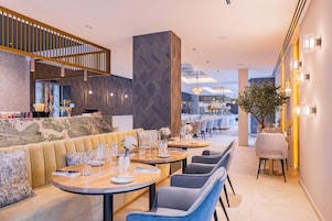 Um restaurante moderno com mesas redondas, assentos confortáveis e vista para as montanhas.