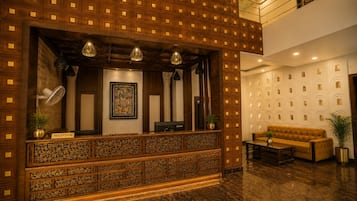 Uma área de recepção com balcão, uma obra de arte emoldurada e um espaço de estar com sofá e mesa.
