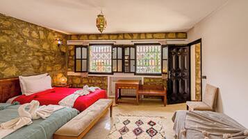 Quarto com duas camas, um banco, uma mesa e um tapete estampado.