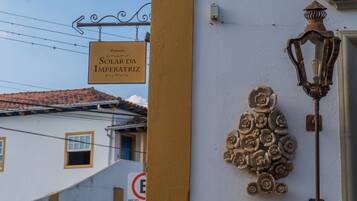 Esquina de um edifício com uma placa indicando 'Pousada Solar da Imperatriz' e uma peça de metal ornamental.
