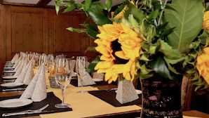 Uma mesa de jantar posta com guardanapos brancos, copos de vinho e um arranjo central com flores amarelas.