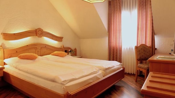 Um quarto com uma cama de madeira, uma cadeira e uma escrivaninha.