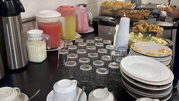 Uma mesa de buffet com diversos alimentos, bebidas e uma estação de café.