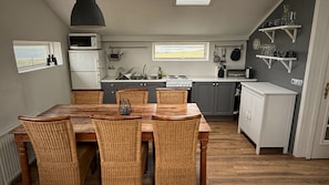 Uma cozinha compacta com uma mesa de jantar e cadeiras, micro-ondas, fogão e pia.
