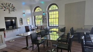 Uma sala de conferências com uma mesa comprida, várias cadeiras e janelas amplas.