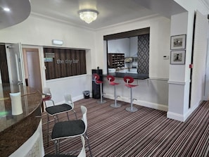 Quarto de hotel com cozinha, bar e área de estar com cadeiras.