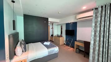 Quarto de hotel moderno com cama, escrivaninha e televisão.