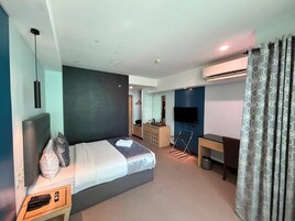Quarto de hotel moderno com cama, escrivaninha e televisão.