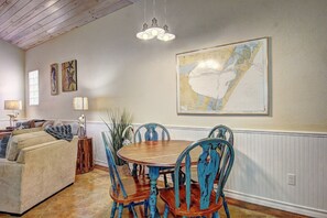 Uma sala de jantar com mesa de madeira e cadeiras azuis, um sofá cor creme e um mapa na parede.
