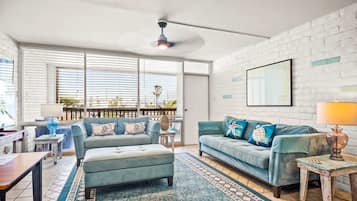 Sala de estar com sofá, apoio para os pés e ventilador de teto.