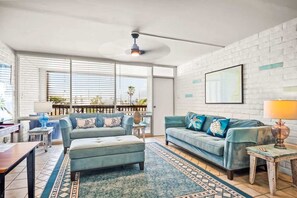 Sala de estar com sofá, apoio para os pés e ventilador de teto.