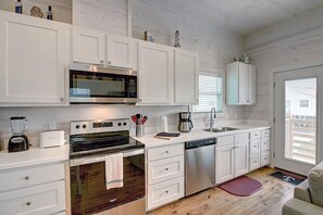 Uma cozinha moderna com armários brancos, eletrodomésticos de aço inoxidável e piso de madeira.