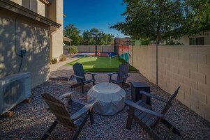 Um pátio externo com mesa e cadeiras, uma área de estar coberta e um cesto de basquete.
