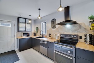 Cozinha moderna com ilha central, eletrodomésticos de aço inoxidável e luminária pendente.