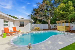 Um quintal com piscina, móveis de exterior e uma árvore.