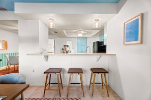 Uma cozinha moderna com uma ilha central, banquetas e um ventilador de teto.