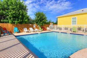Uma piscina com espreguiçadeiras e um deck de madeira.