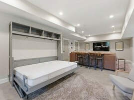 Quarto com cama, escrivaninha e televisão exibindo 'Home Team'.