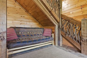 Interior em madeira com um sofá, almofadas e um detalhe decorativo na parede.
