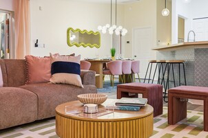 Uma sala de estar moderna com sofá, mesa de centro e um espaço de jantar com cadeiras e uma pequena mesa.