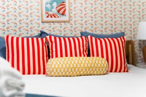 Uma cama com almofadas listradas e um travesseiro estampado.
