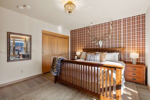 Quarto com cama de madeira, mesa de cabeceira, espelho e parede com padrão xadrez.