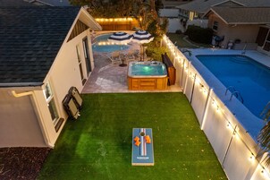 Um quintal com piscina, ofurô e área de deck com cadeiras e guarda-sóis.