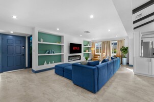 Uma sala de estar moderna com um sofá azul, uma TV de tela plana e uma lareira.