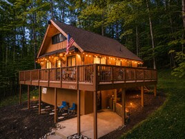 Uma cabana de madeira com varanda, uma bandeira e área de estar externa.