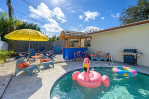 Um quintal com piscina, boia de flamingo inflável e área de estar ao ar livre.