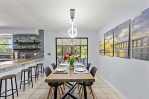 Uma área de jantar moderna com uma mesa de madeira, cadeiras pretas e um vaso de tulipas vermelhas.