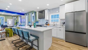 A modern kitchen with a central island, stainless steel appliances, and a dining area with bar stools.