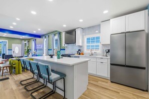 A modern kitchen with a central island, stainless steel appliances, and a dining area with bar stools.