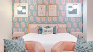 Quarto com cama, duas mesas de cabeceira e quadros nas paredes.