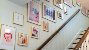 Uma escadaria com corrimão e várias molduras com fotos na parede.