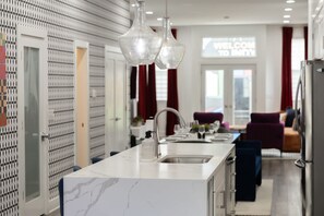 Uma cozinha moderna com bancada de mármore, pia de aço inoxidável e luminárias pendentes.