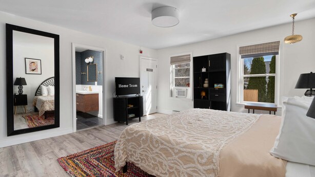 Quarto com cama grande, televisão, guarda-roupa e espelho.