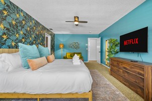 Quarto com cama, televisão e ventoinha no teto.