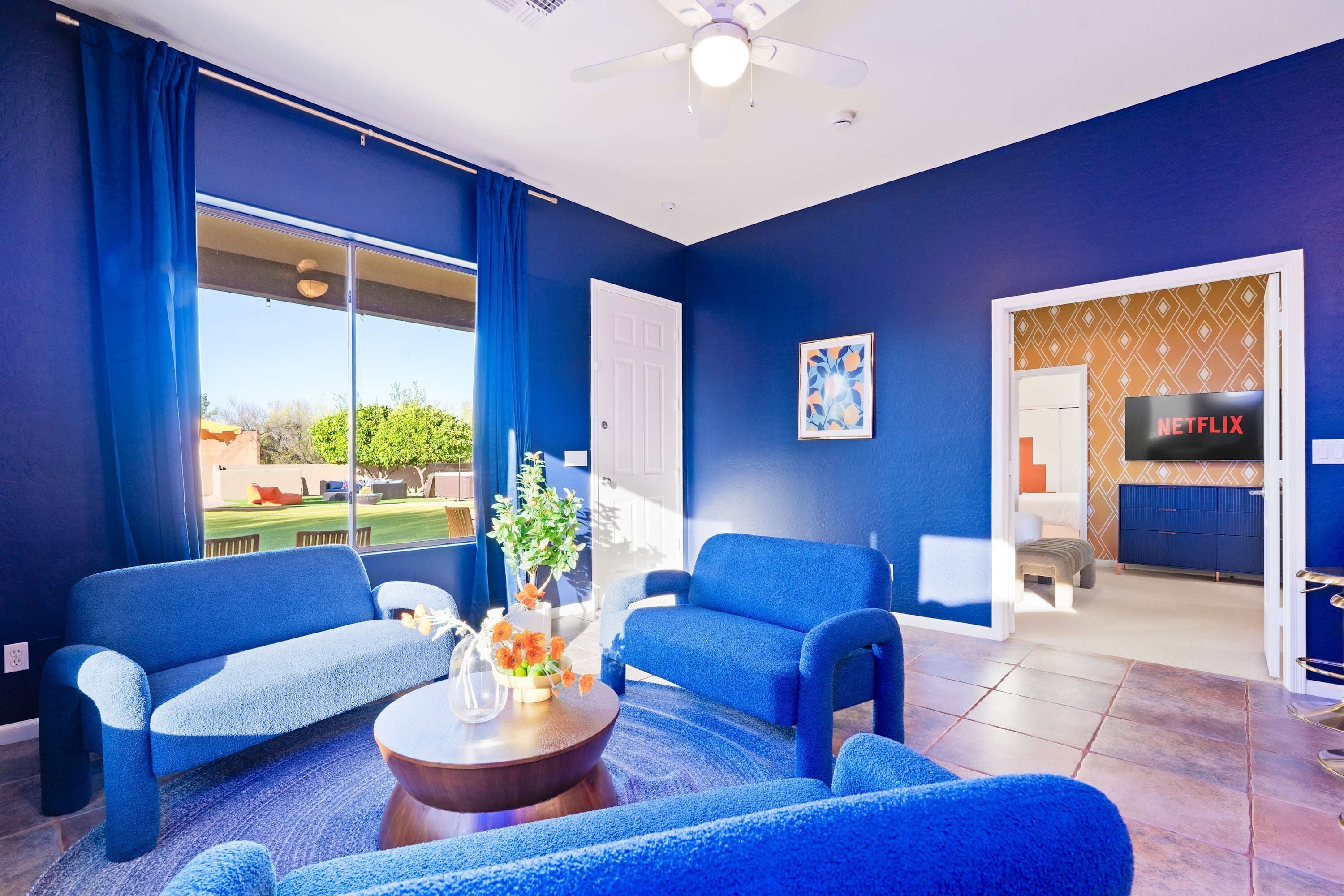 A living room with two blue sofas, a coffee table, and a TV in the background.