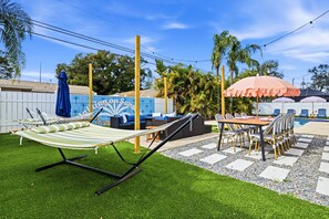 Um quintal com rede, área de estar externa e piscina.