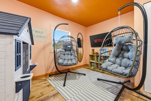 Um quarto com duas cadeiras suspensas, uma estante de livros e um letreiro que diz 'WILD CHILD'.