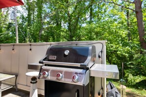 Um grill Spirit portátil com painel de controle, montado ao ar livre com vista para uma área arborizada.